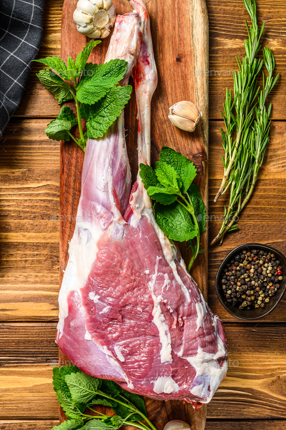 Goat leg with pepper and garlic. Raw Farm meat. Wooden background. Top ...