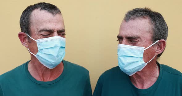 Senior twin brothers looking while wearing safety face masks for ...