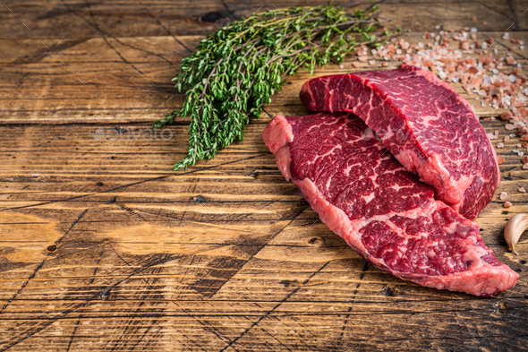Raw denver or top blade meat steak on a butchery table with herbs ...