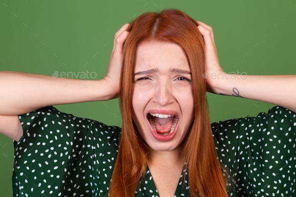 Young red hair woman on green background sad angry screaming crying ...