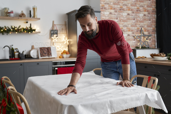 Man setting table for Christmas eve Stock Photo by gpointstudio | PhotoDune