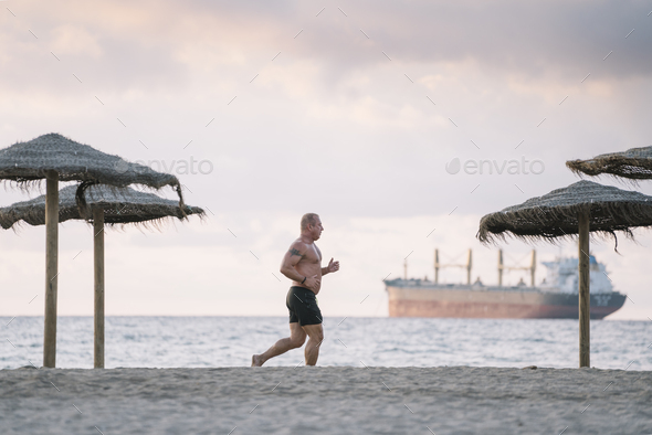 Strong old man makes exercise on the beach. Stock Photo by ADDICTIVE_STOCK