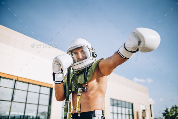 Man practicing boxing with astronaut helmet. Stock Photo by ADDICTIVE_STOCK