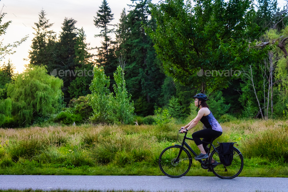 Woman riding a road bicycle on a bike path at the famous Stanley Park ...