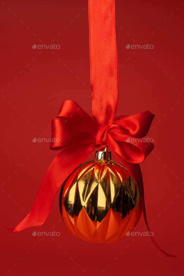 Beautiful christmas bauble hanging on red satin ribbon against red ...