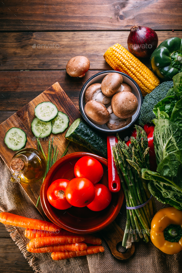 Vegetables and utensils on kitchen table Stock Photo by ADDICTIVE_STOCK