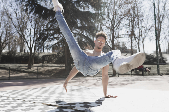 Shirtless man dancing break dance in park Stock Photo by ADDICTIVE_STOCK