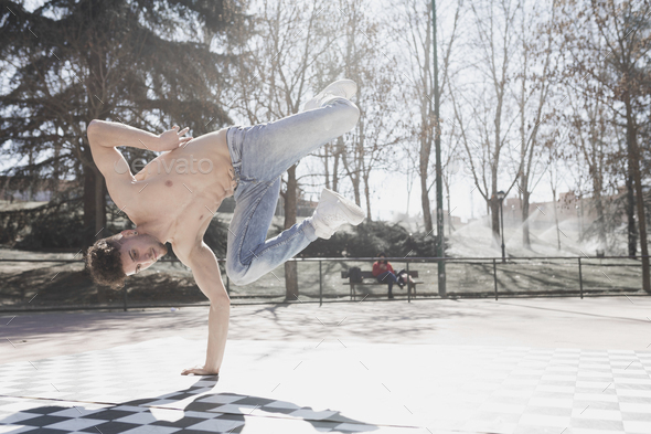Shirtless man dancing break dance in park Stock Photo by ADDICTIVE_STOCK