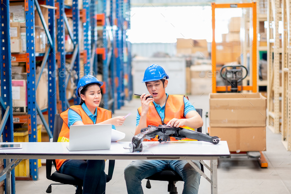 Warehouse man and woman or factory workers sit on chairs and discuss ...