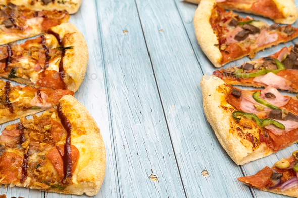 Lots of delicious triangular pizza slices on a blue wooden background ...