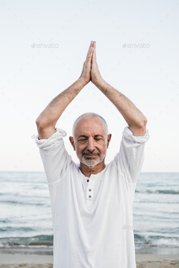Senior man doing yoga meditation outdoor at the beach - Elderly and ...
