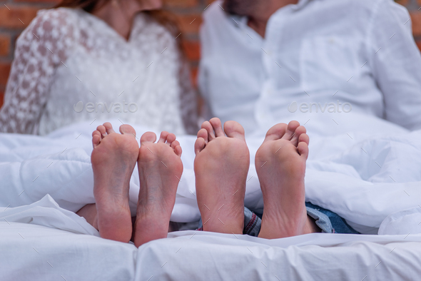 From under the white she covered two pairs of feet of couple in love ...