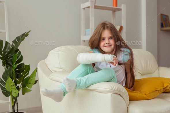 Child with a cast on a broken wrist or arm smiling and having fun on a ...