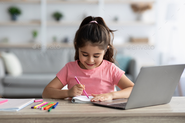 Little Girl Drawing In Notepad While Study Online With Laptop At Home ...