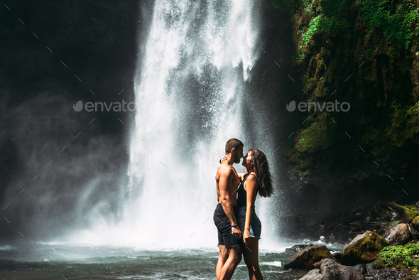 Beautiful couple kissing at the waterfall. A couple in love at a ...