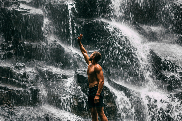 A man of athletic build at the waterfall. A man travels the world. Man ...