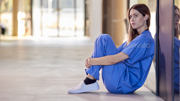Tired And Overworked Medical Worker In Scrubs Sitting On Floor Of ...