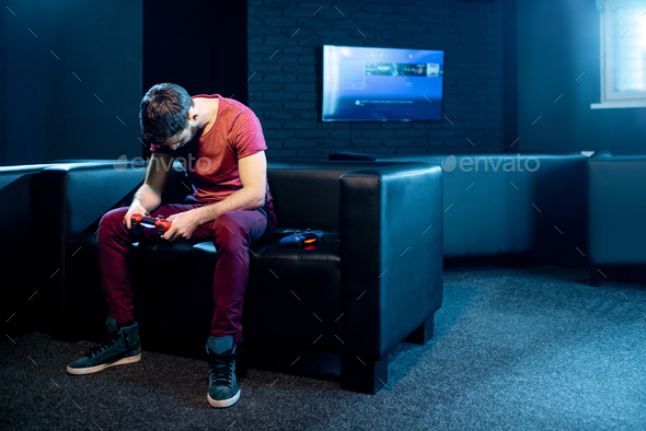 Sad man playing video games with gaming console in the club Stock Photo ...