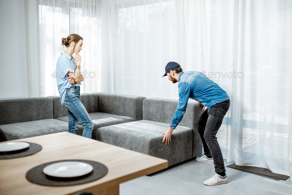 Man mounting sofa with woman in the apartment Stock Photo by RossHelen