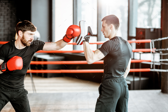 Man training with boxing coach on the boxing ring Stock Photo by RossHelen