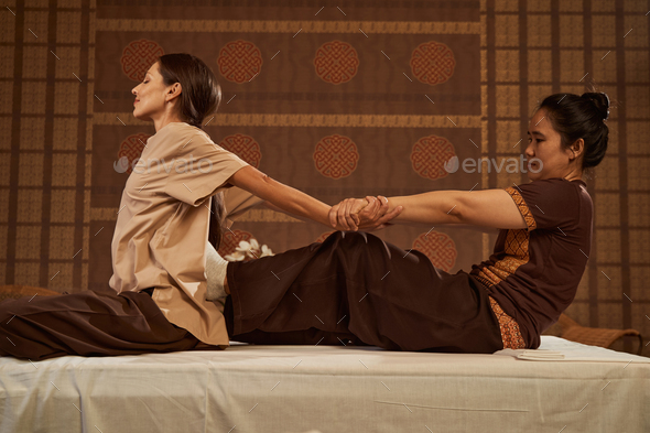 Thai masseuse stretching client during massage session Stock Photo by ...