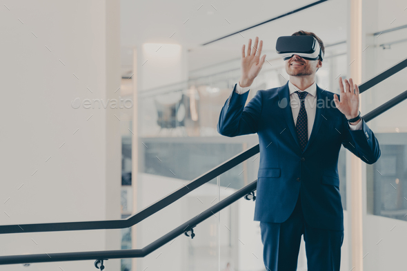 Impressed male office worker wearing VR goggles exploring virtual world ...