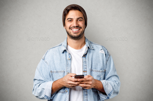 Handsome millennial guy with smartphone Stock Photo by claudioventrella