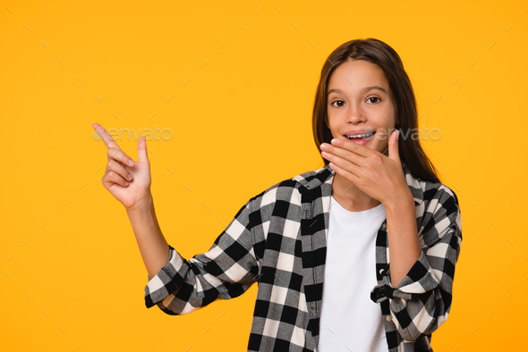Teenager girl schoolkid pupil student laughing pointing at copy space ...
