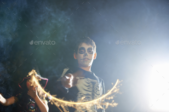Brother and sister wearing halloween costumes playing with sparklers in ...