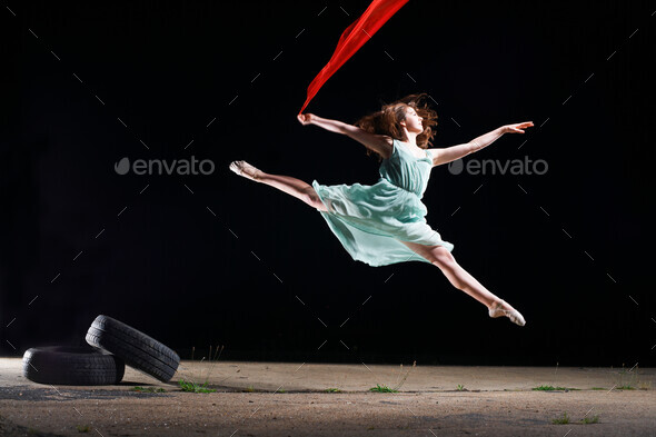 Ballet dancer leaping mid air holding red scarf Stock Photo by nualaimages