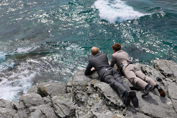 Businessmen peering over cliff edge Stock Photo by nualaimages | PhotoDune