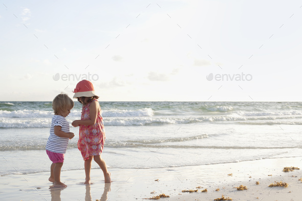 Siblings exploring on the beach at sunset Stock Photo by ImageSourceCur