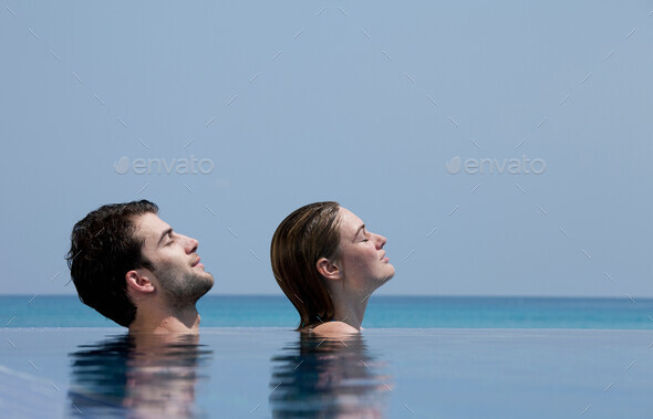 Couple relaxing in infinity pool Stock Photo by nualaimages | PhotoDune