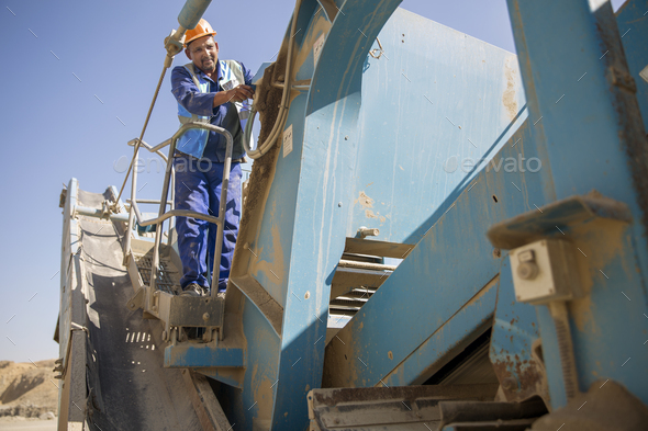 Quarry worker working on heavy machinery Stock Photo by nualaimages