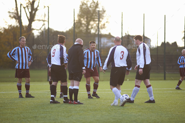 Referee and football players settling dispute Stock Photo by nualaimages