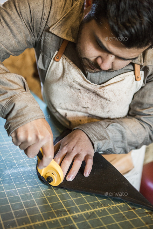 Tailor using rotary cutter on fabric on workshop bench Stock Photo by ...