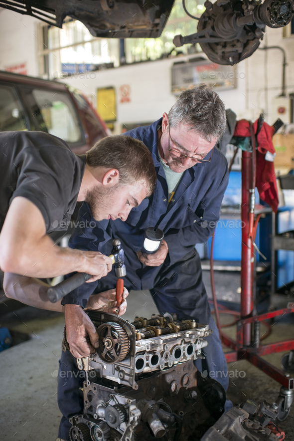 Mechanics working on car engine in garage Stock Photo by ImageSourceCur