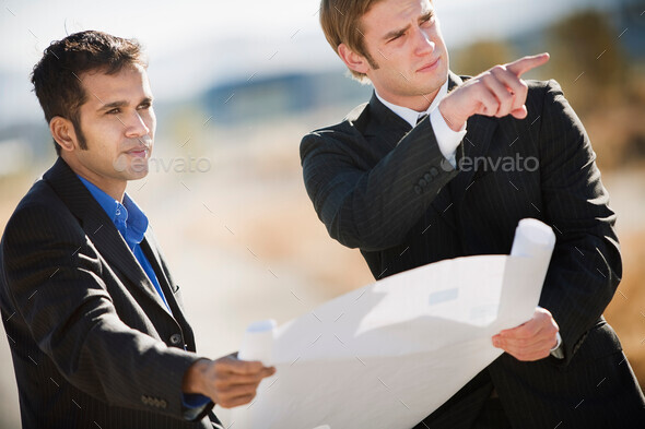 2 men with blueprints outside pointing Stock Photo by nualaimages ...