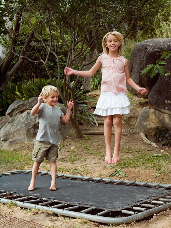 Brother and sister bouncing on trampoline Stock Photo by ImageSourceCur
