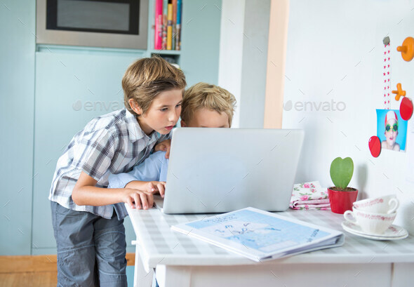 Brothers looking at laptop together Stock Photo by nualaimages | PhotoDune