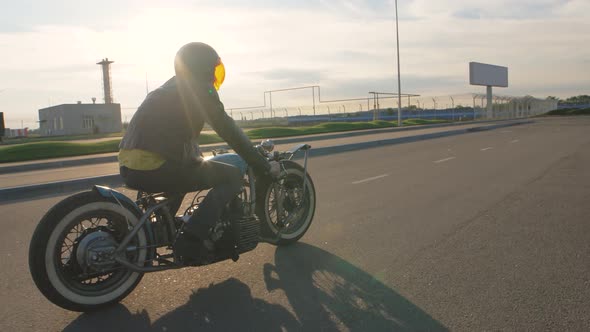 Young Man Biker with Custom Bobber Motorcycle on Street at Sunset ...