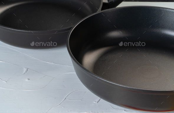 Clean and dry cooking pans on a kitchen counter Stock Photo by FabrikaPhoto