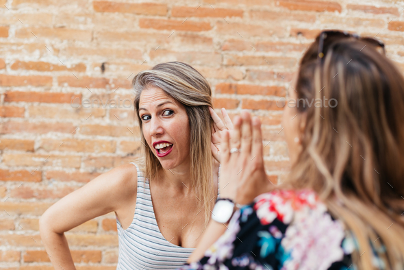 Two friends telling each other a secret on the street Stock Photo by ...