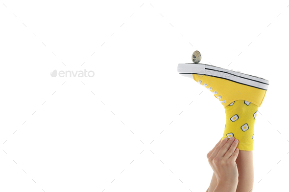 Woman pull up sock on leg in sneaker with quail egg, isolated on white ...
