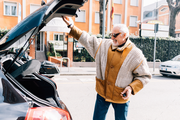 Man holding up car boot door, Milan, Italy Stock Photo by Image-Source