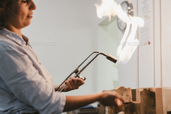 Female jeweller using flaming blow torch at workbench Stock Photo by ...
