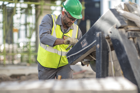 Construction worker using heavy machinery Stock Photo by Image-Source