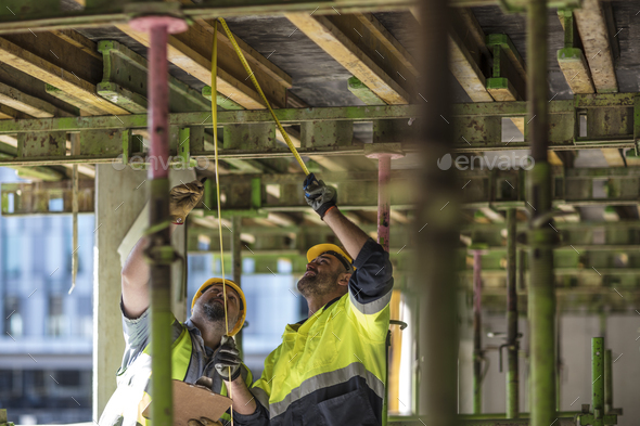 Construction workers measuring building Stock Photo by Image-Source