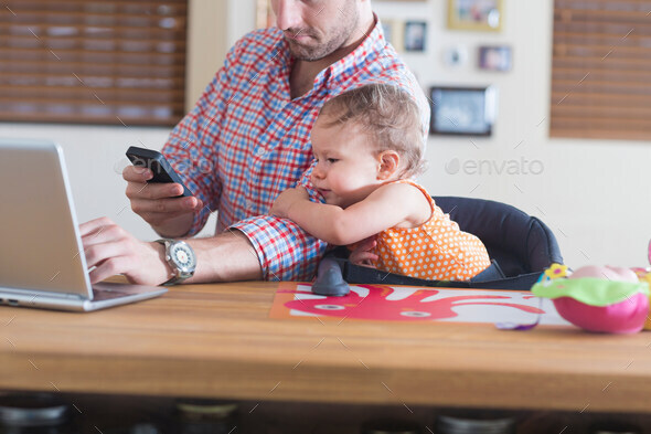 Man working at kitchen counter with baby sitting beside Stock Photo by ...