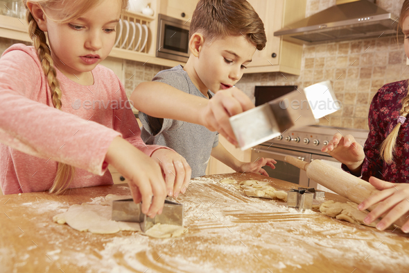 Girls and boy baking star shape pastry at kitchen table Stock Photo by ...